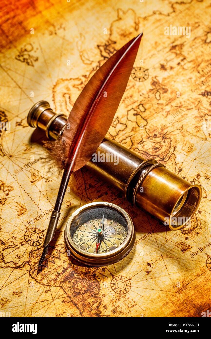 Vintage compass, goose quill pen, and spyglass lying on an old map ...