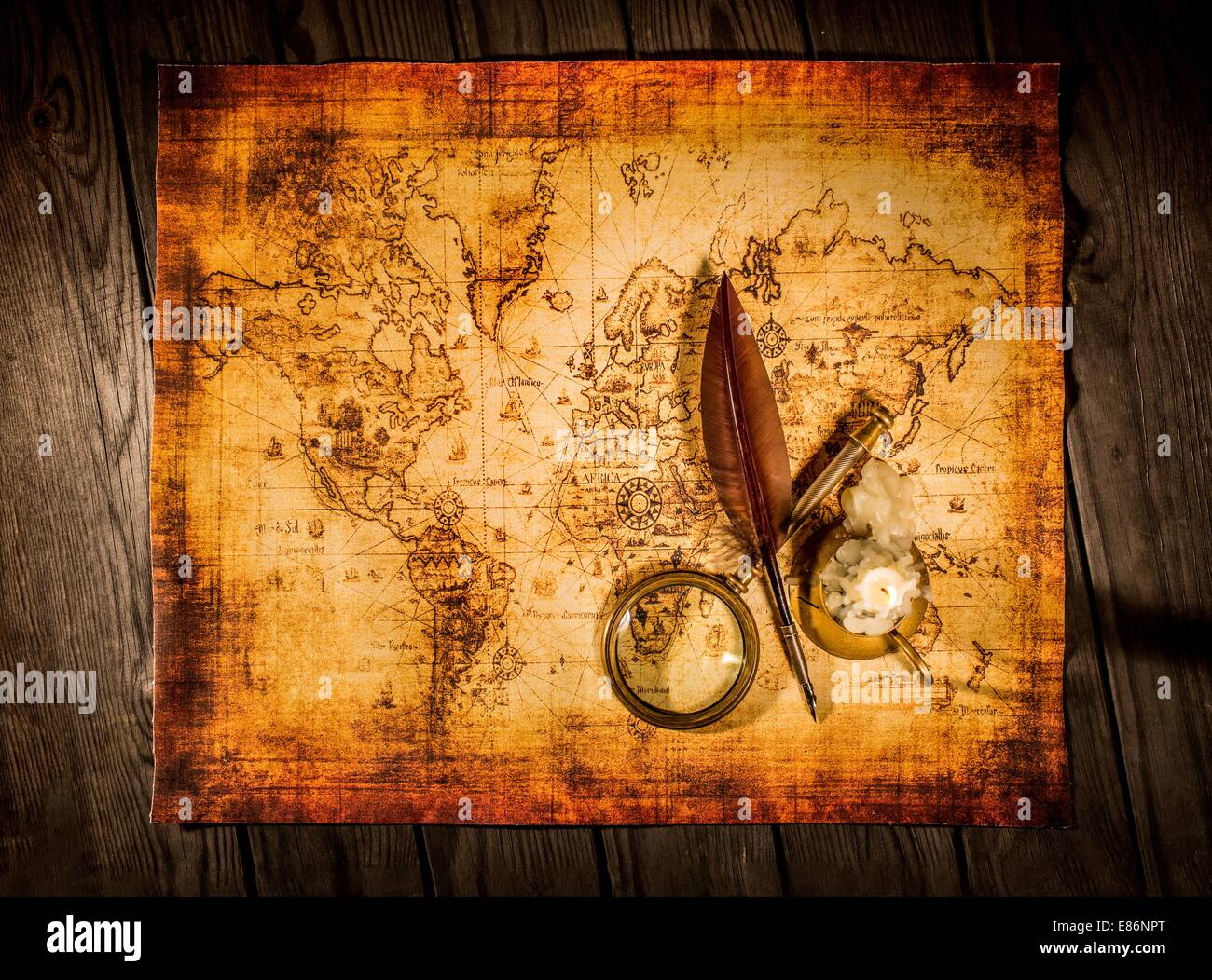 Vintage quill pen and magnifying glass lie on an old ancient map with a ...