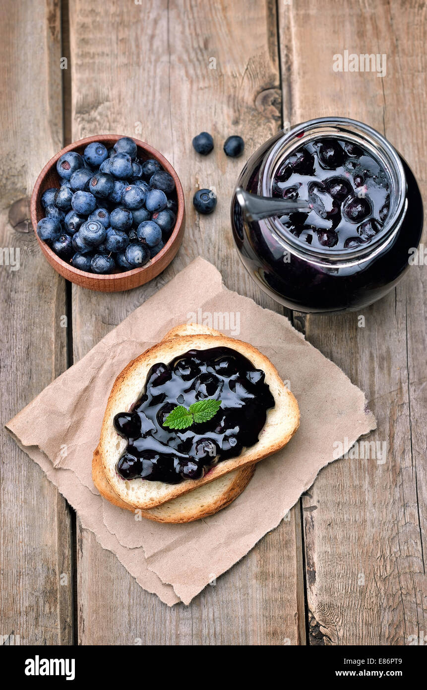 Toasted bread with blueberry jam and jam in glass jar on wooden table ...