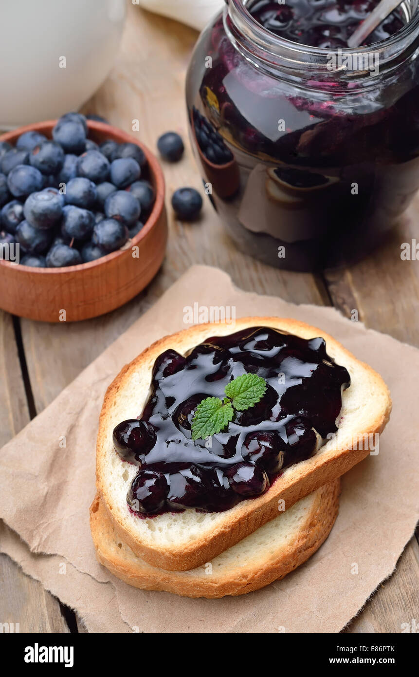 Toasted bread with blueberry jam and jam in glass jar on wooden table ...