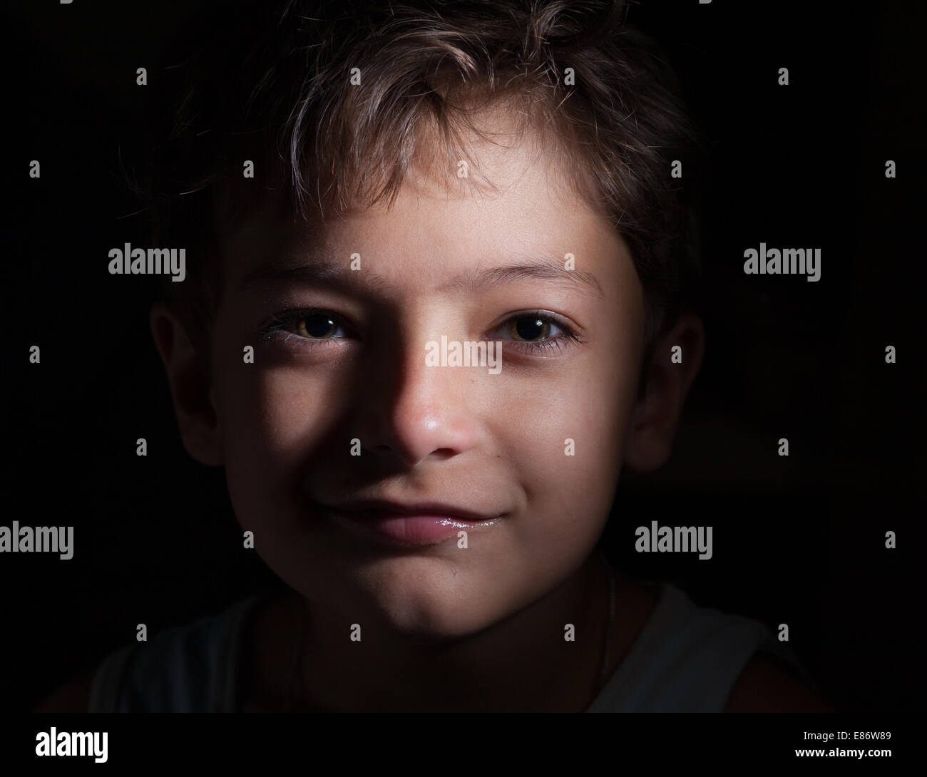 boy look at camera in the dark, focused light on the face only Stock ...