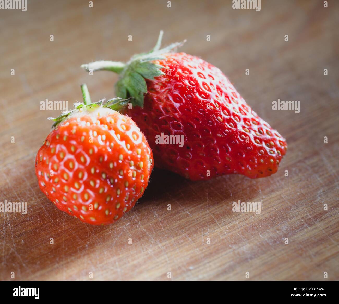 two strawberryes on the wooden plank, side view Stock Photo - Alamy