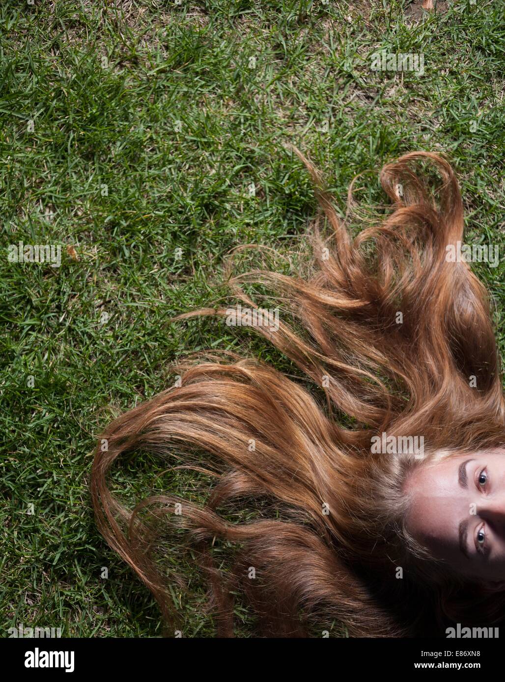 Blond haired 20s female on the green grass - part of the face. Looking ...