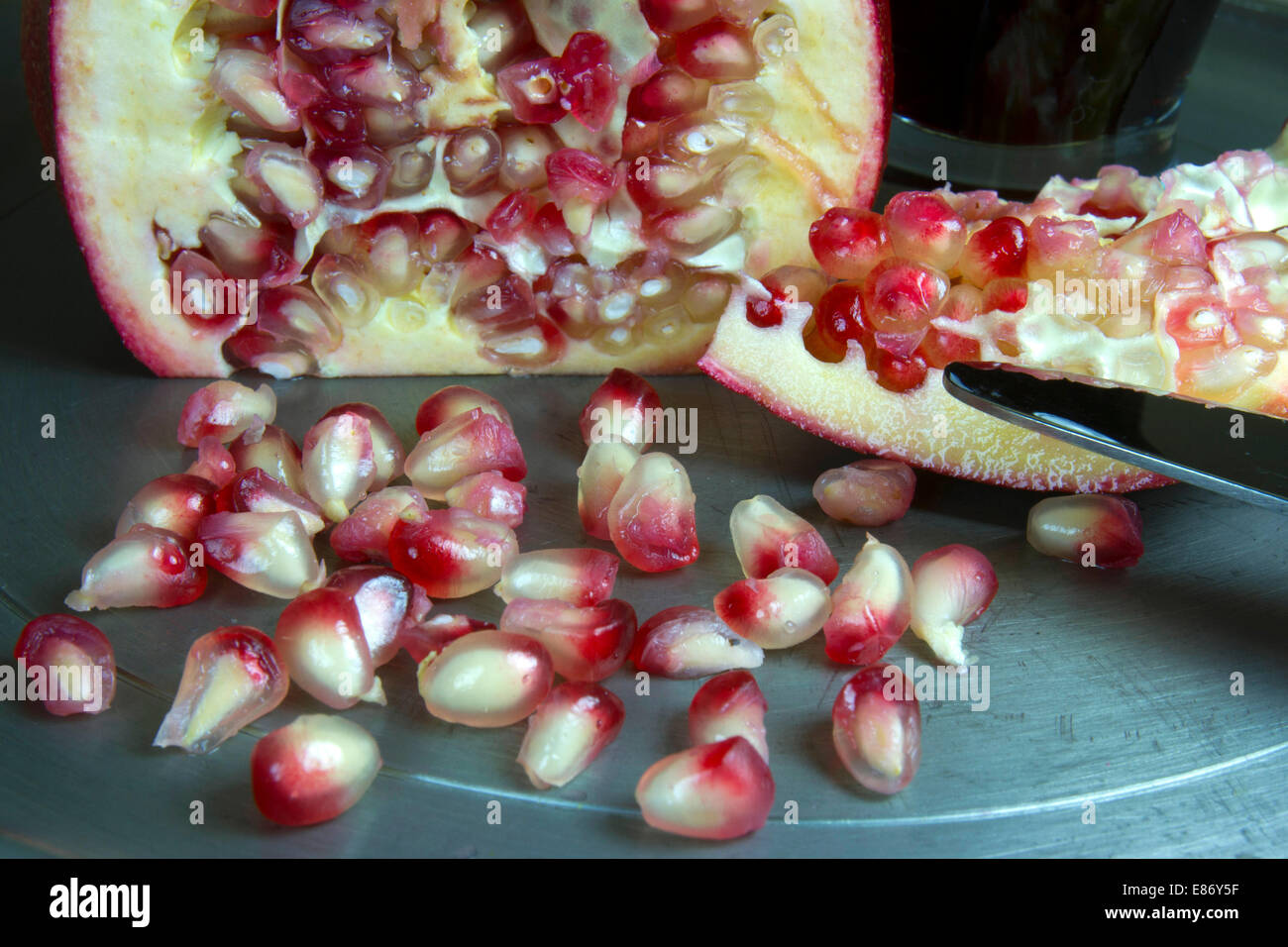 Cross section of a pomegranate with loose seeds on pewter plate Stock ...