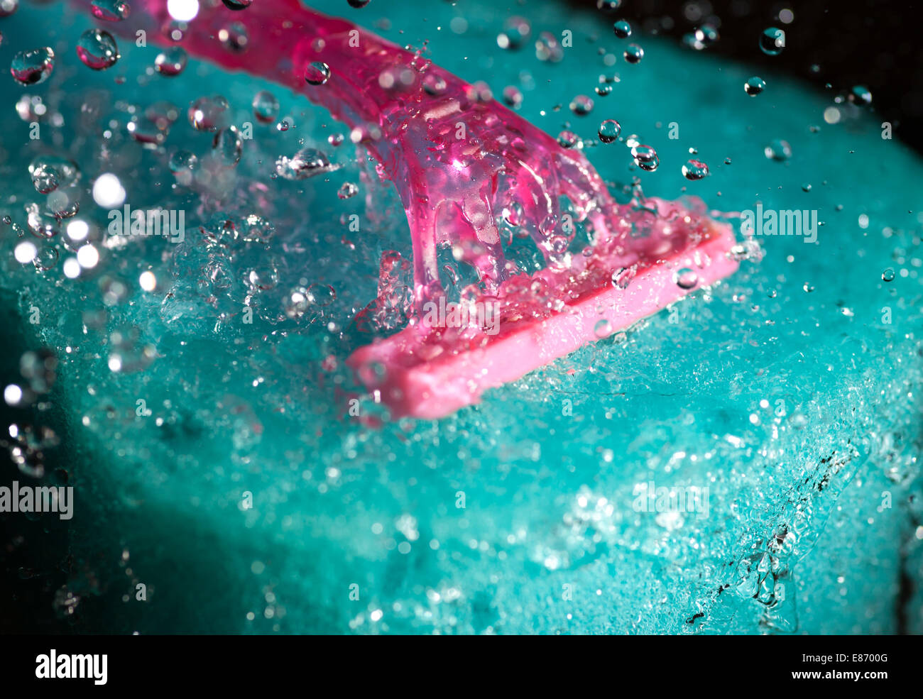 pink women shaving tool on the blue bath sponge, closeup with flying ...