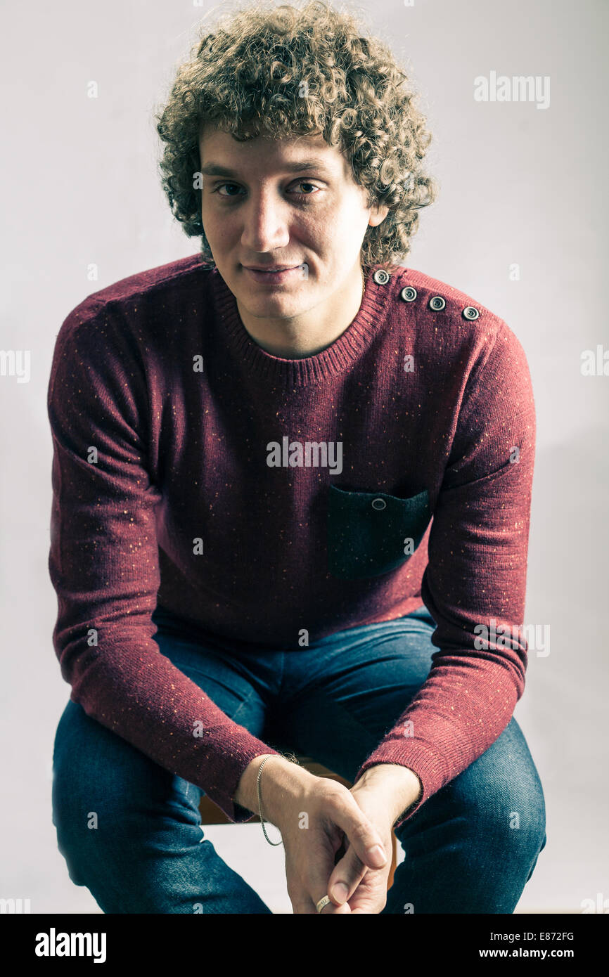 Curly white man in studio sitting front view Stock Photo - Alamy