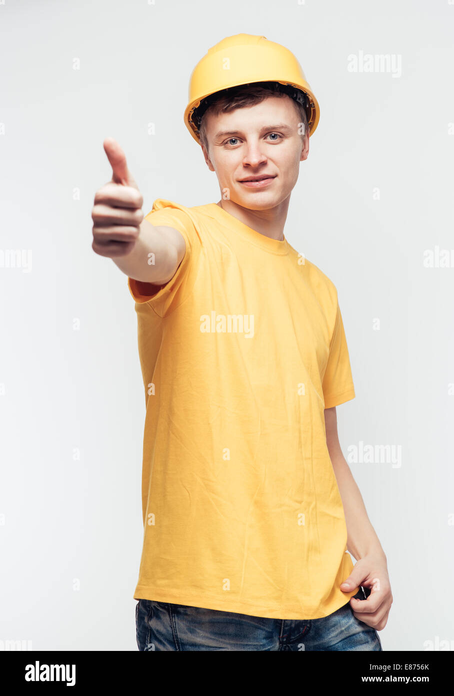 Worker in yellow helmet holding thumb up Stock Photo - Alamy