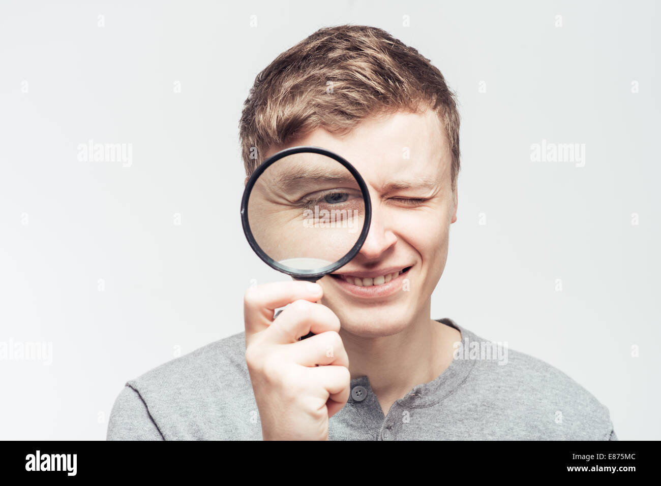 Man looking through a magnifying glass Stock Photo - Alamy