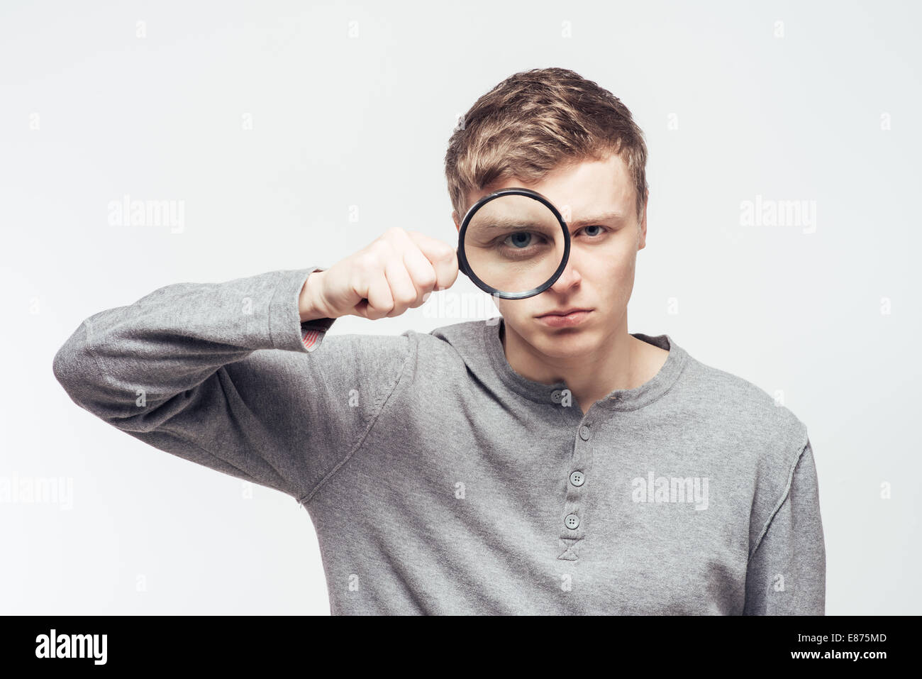 Man looking through a magnifying glass Stock Photo - Alamy