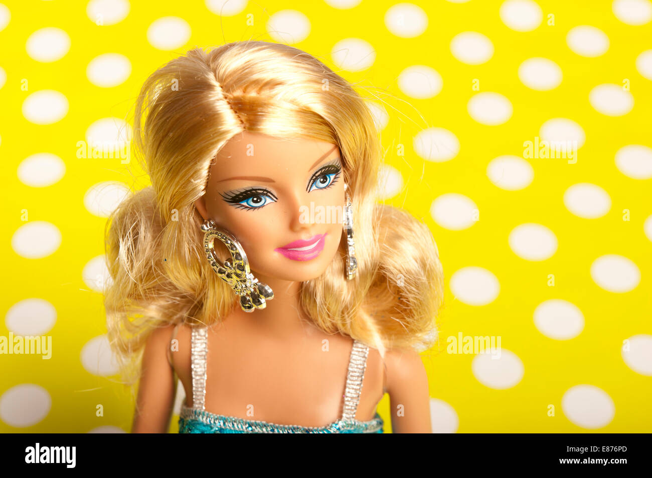 Barbie doll in blue dress against a yellow background Stock Photo - Alamy