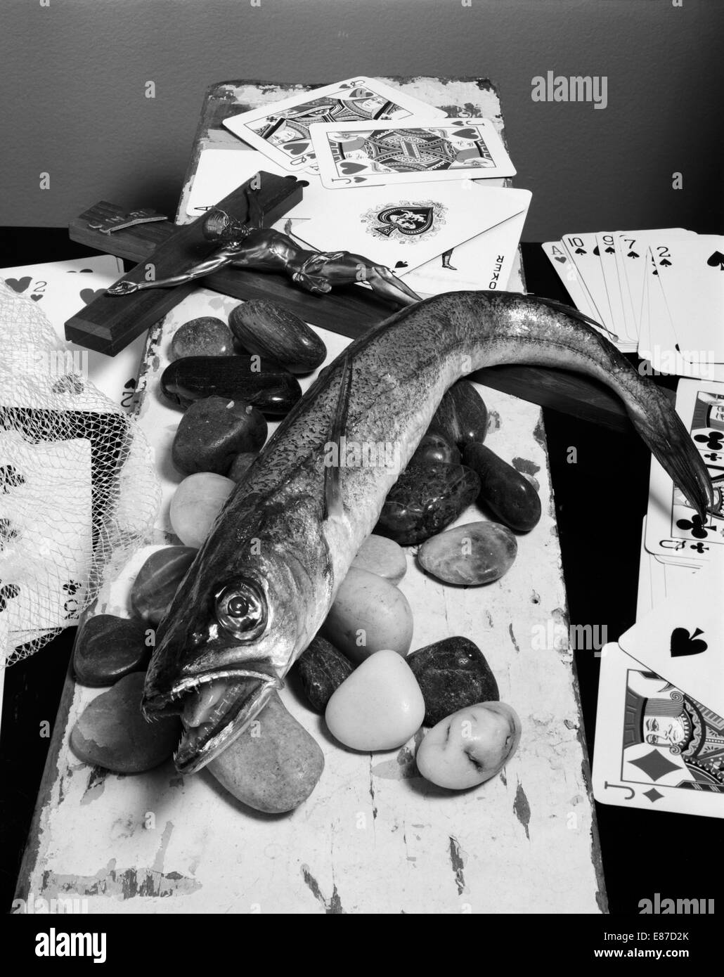 Dead fish lying on the stones with the Cross and playing cards Stock ...