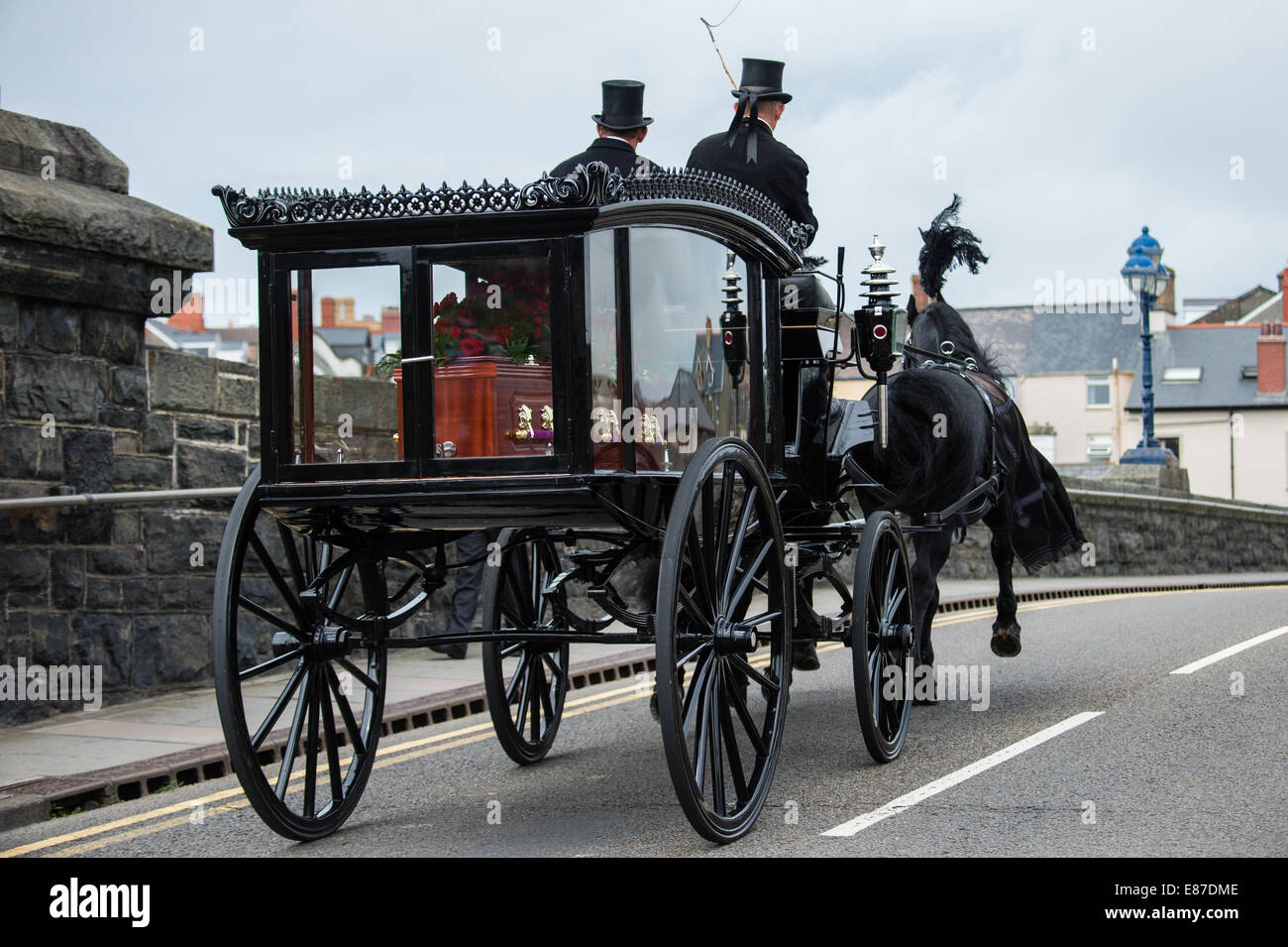 Two undertakers riding driving a sombre black Victorian era traditional ...
