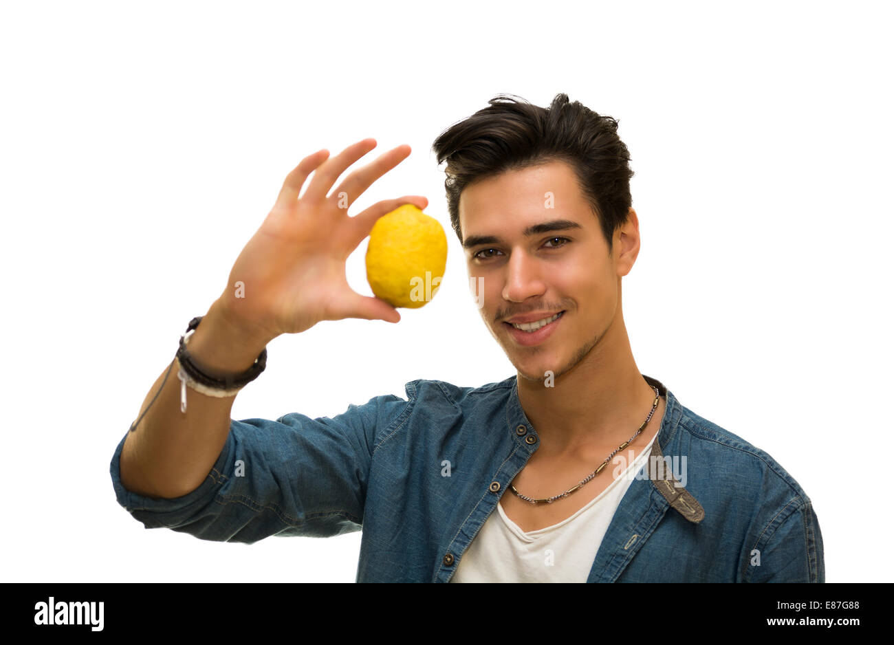 Smiling young man holding a fresh lemon in his hand in a healthy diet ...