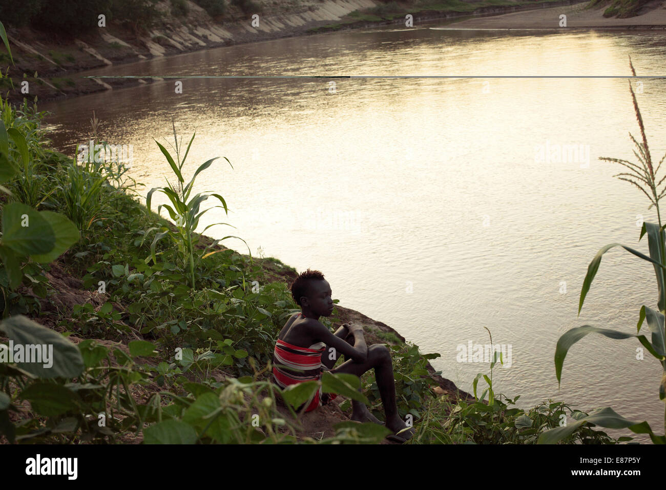 A boy wathces the Omo river as one of water source for Gibe III Dam ...