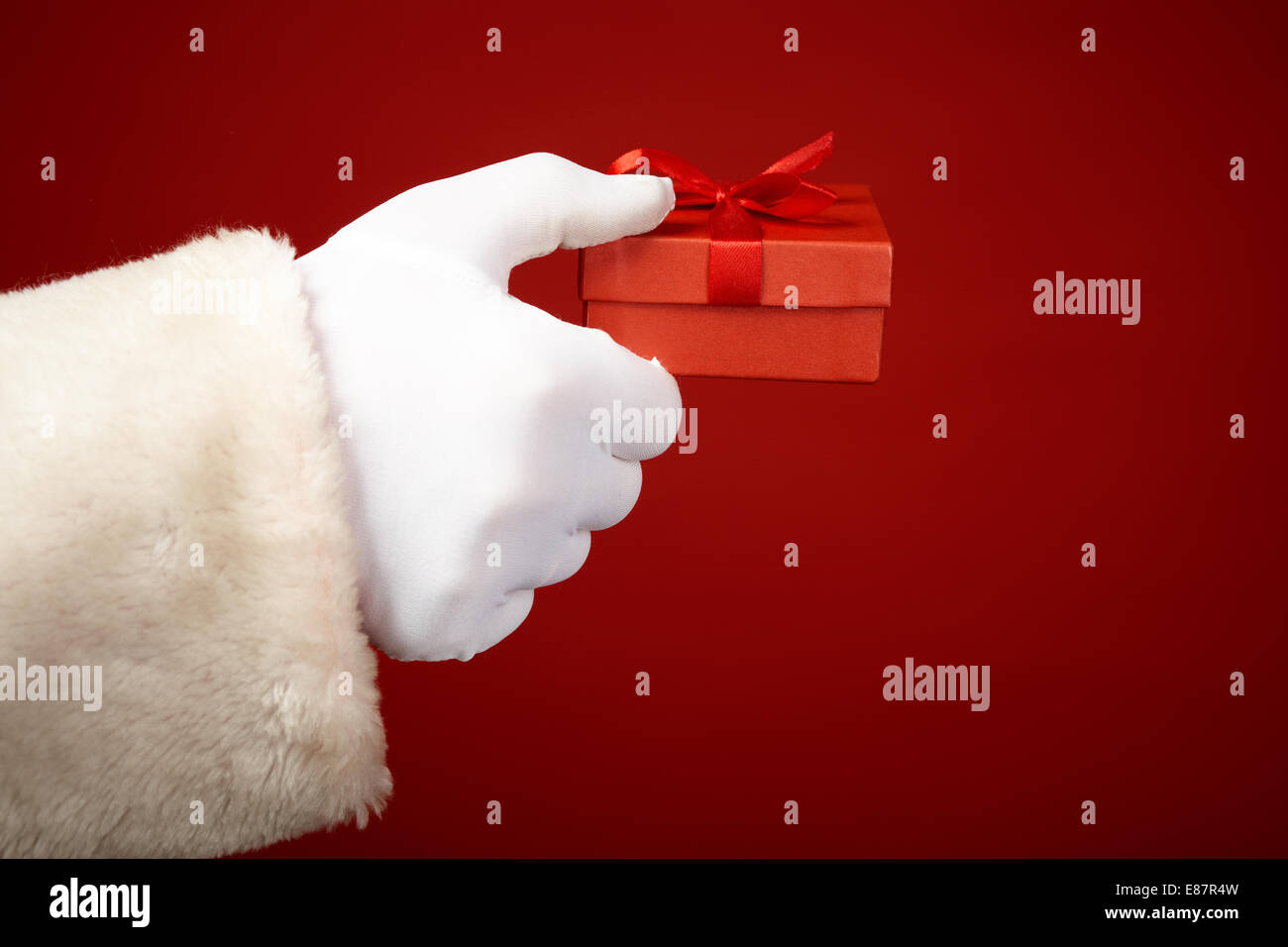 Santa Claus hand in white glove holding small red giftbox Stock Photo ...