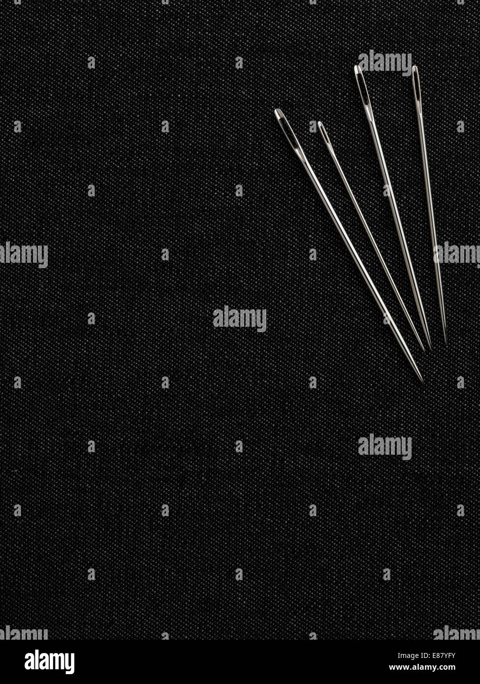 Needles on textured denim background Stock Photo - Alamy