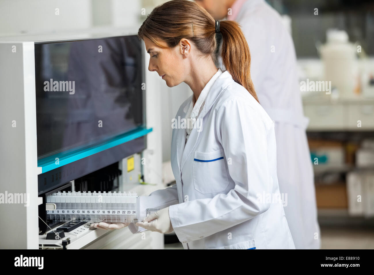 Female Researcher Loading Samples In Analyzer Stock Photo - Alamy