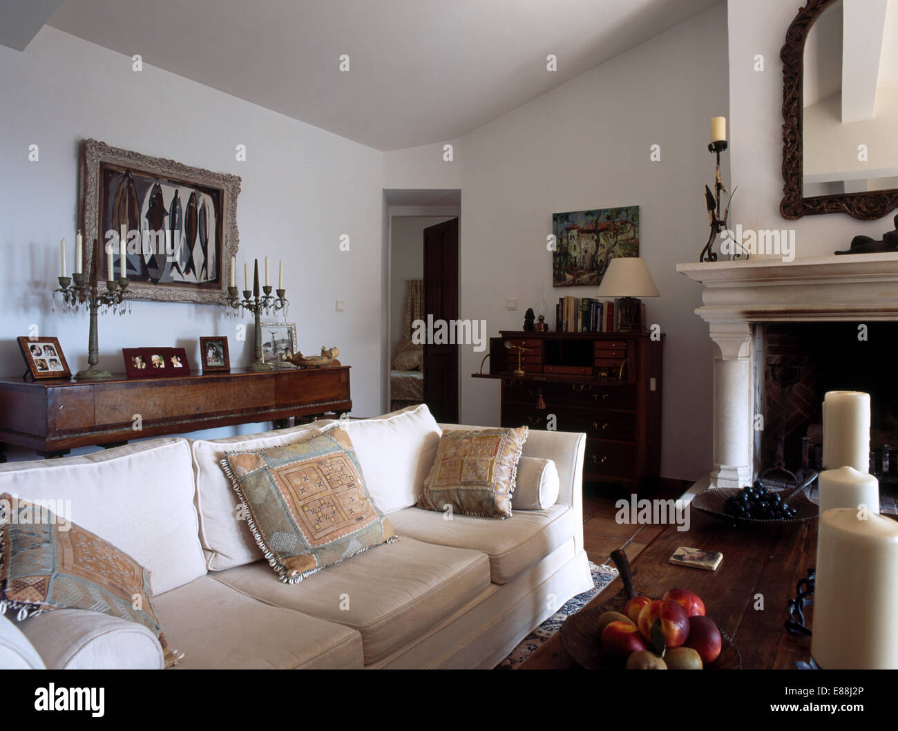 Cream sofa in French country livingroom with white walls and fireplace ...