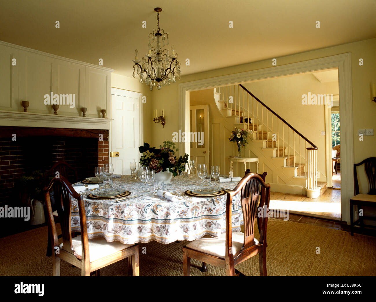 Place settings and floral cloth on table in country dining room with ...