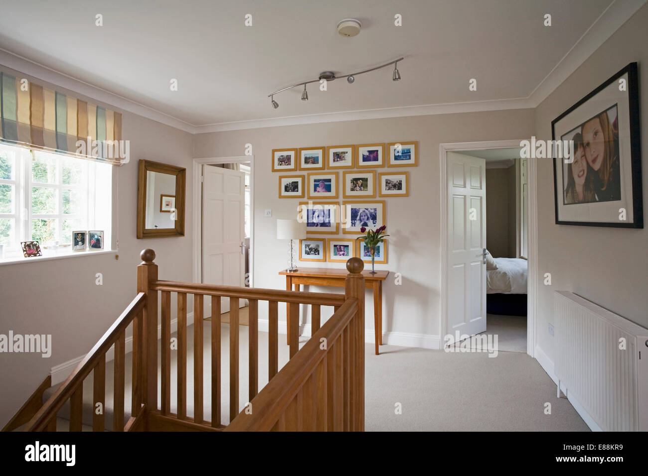 Pictures displayed on wall above console table on landing with pale ...
