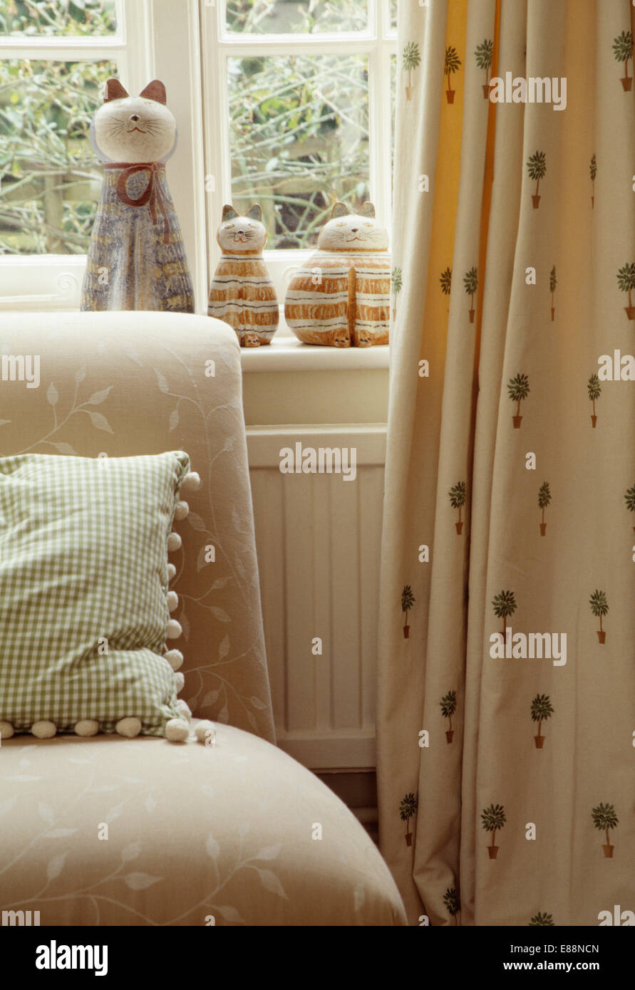 Close-up of bobble-edged cushion on beige sofa in front of window with ...
