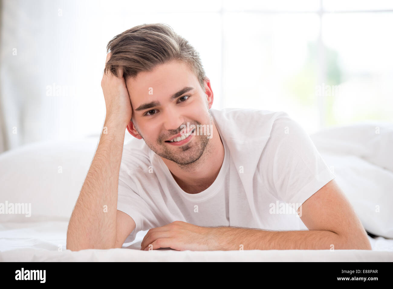 Smiling young man in the bed Stock Photo - Alamy