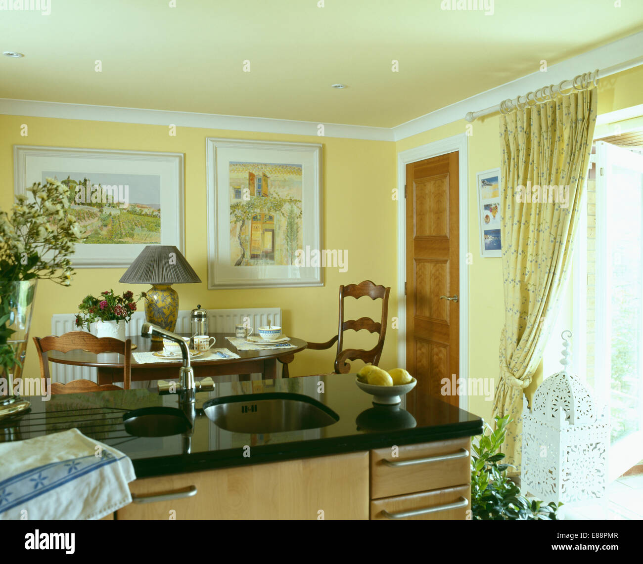 Granite topped island unit dividing traditional yellow kitchen and ...