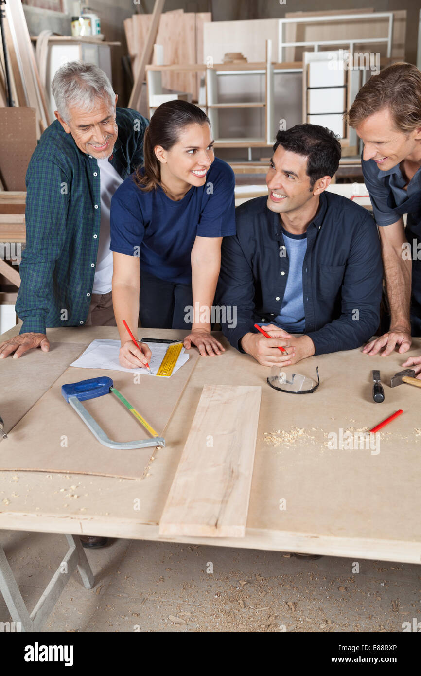 Female Carpenter Working On Blueprint With Team Stock Photo - Alamy