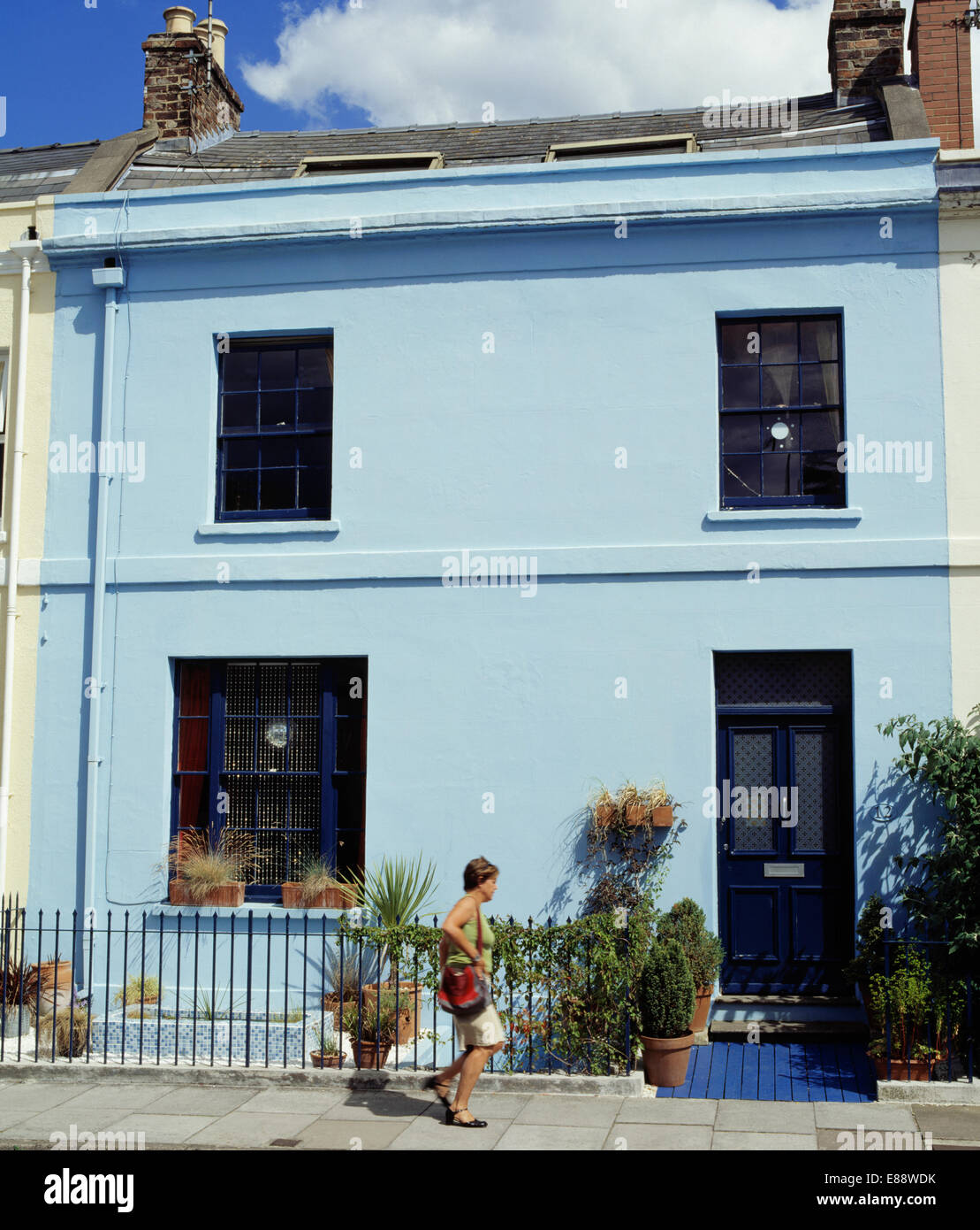 Woman walking past newly-painted pale blue townhouse Stock Photo - Alamy