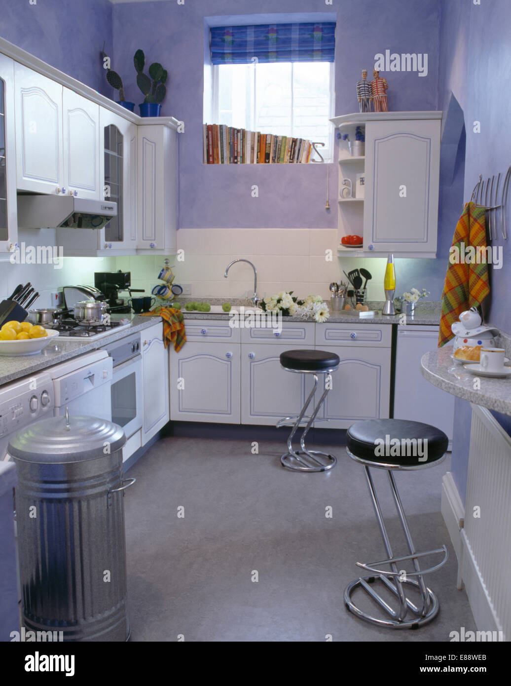 Chrome+leather stools in mauve kitchen with large metal waste bin Stock ...