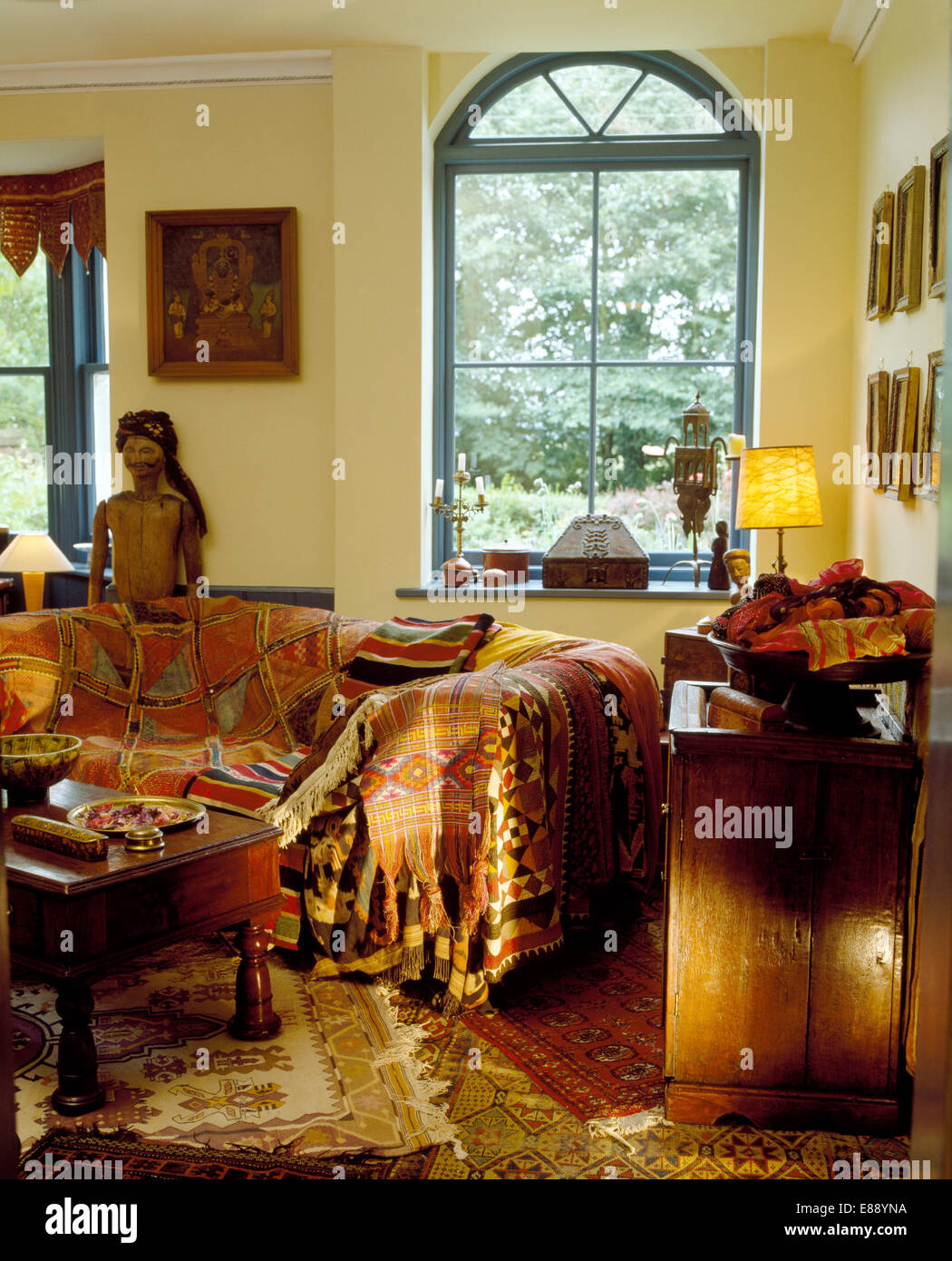 Arched window above sofa with Indian throw in country living room with ...