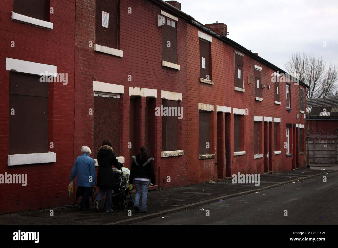 Women and a child walk passed boarded up houses in Beswick North ...