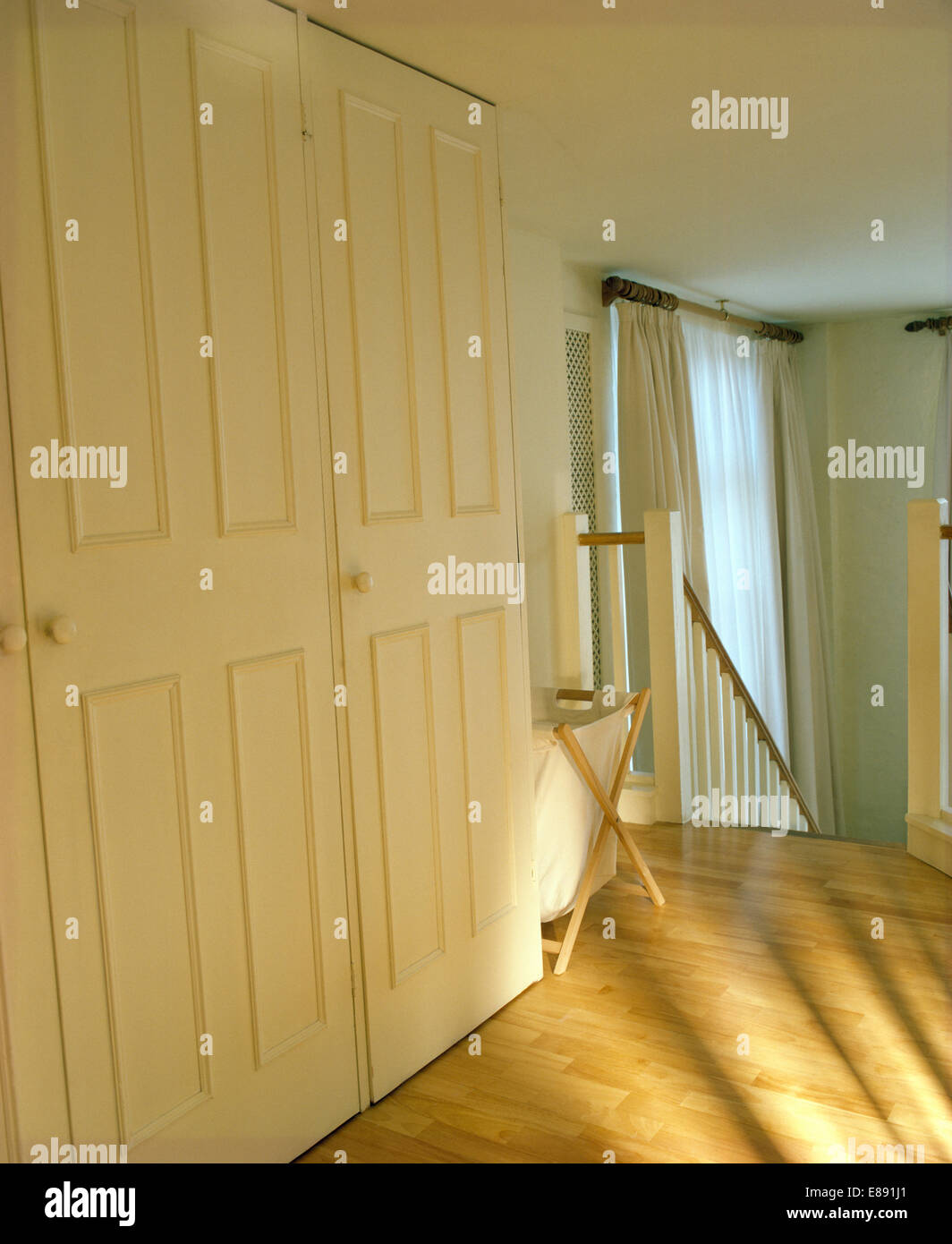 Fitted cream-painted wardrobe and wooden flooring on landing in country ...