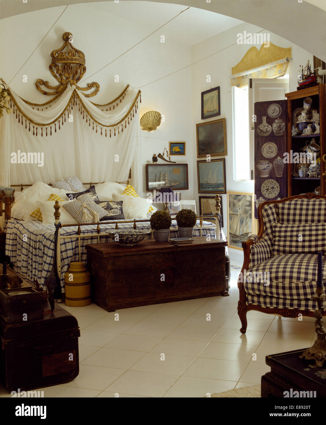 Blue+white checked armchair and antique chests in bedroom with white ...