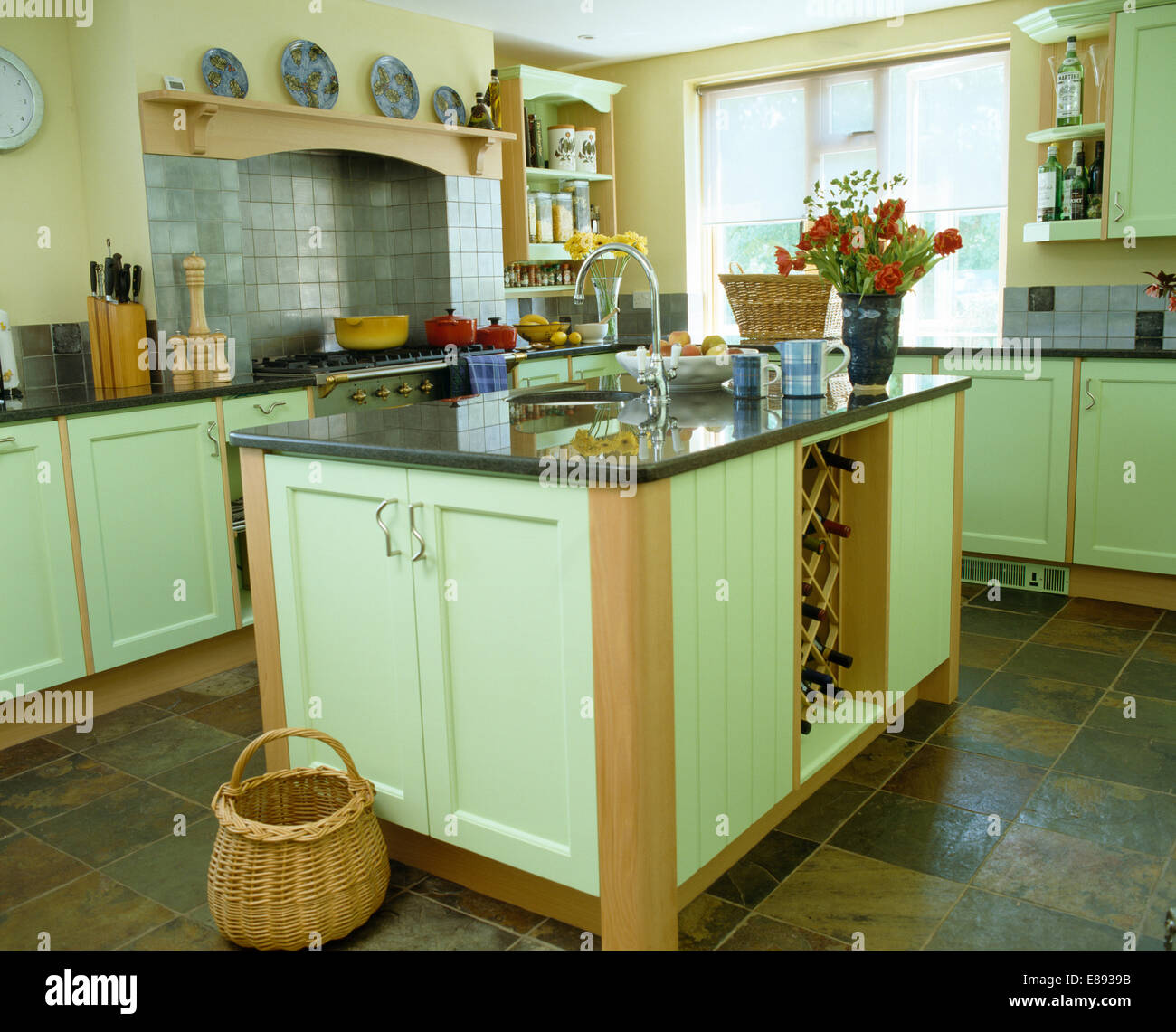 Granite topped island unit in country kitchen with pale green fitted ...