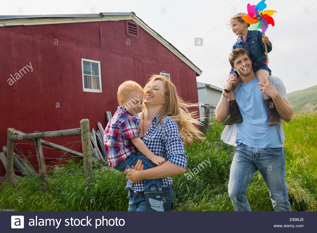 Parents carrying children outside barn Stock Photo - Alamy
