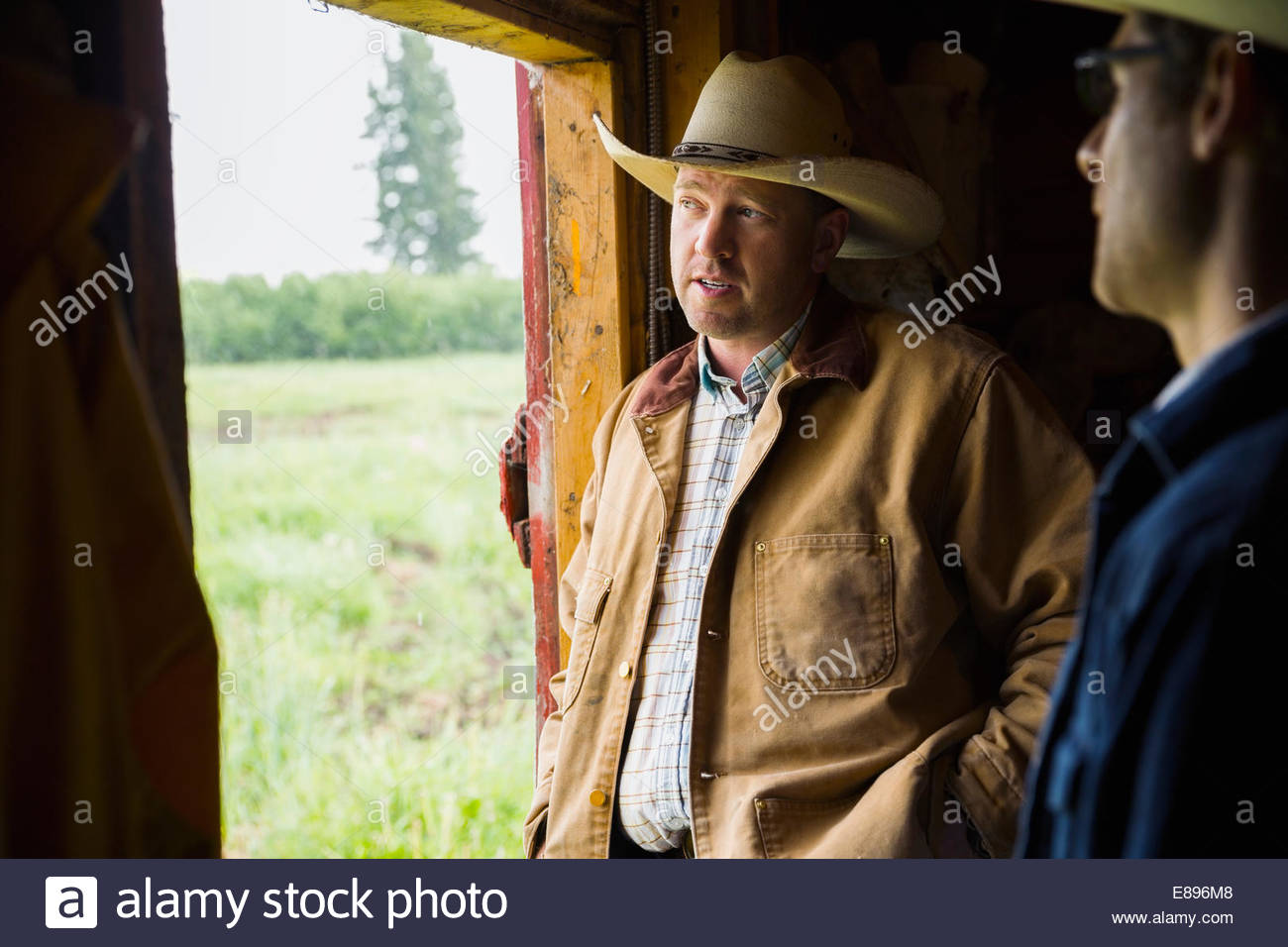 Ranchers talking in barn doorway Stock Photo - Alamy