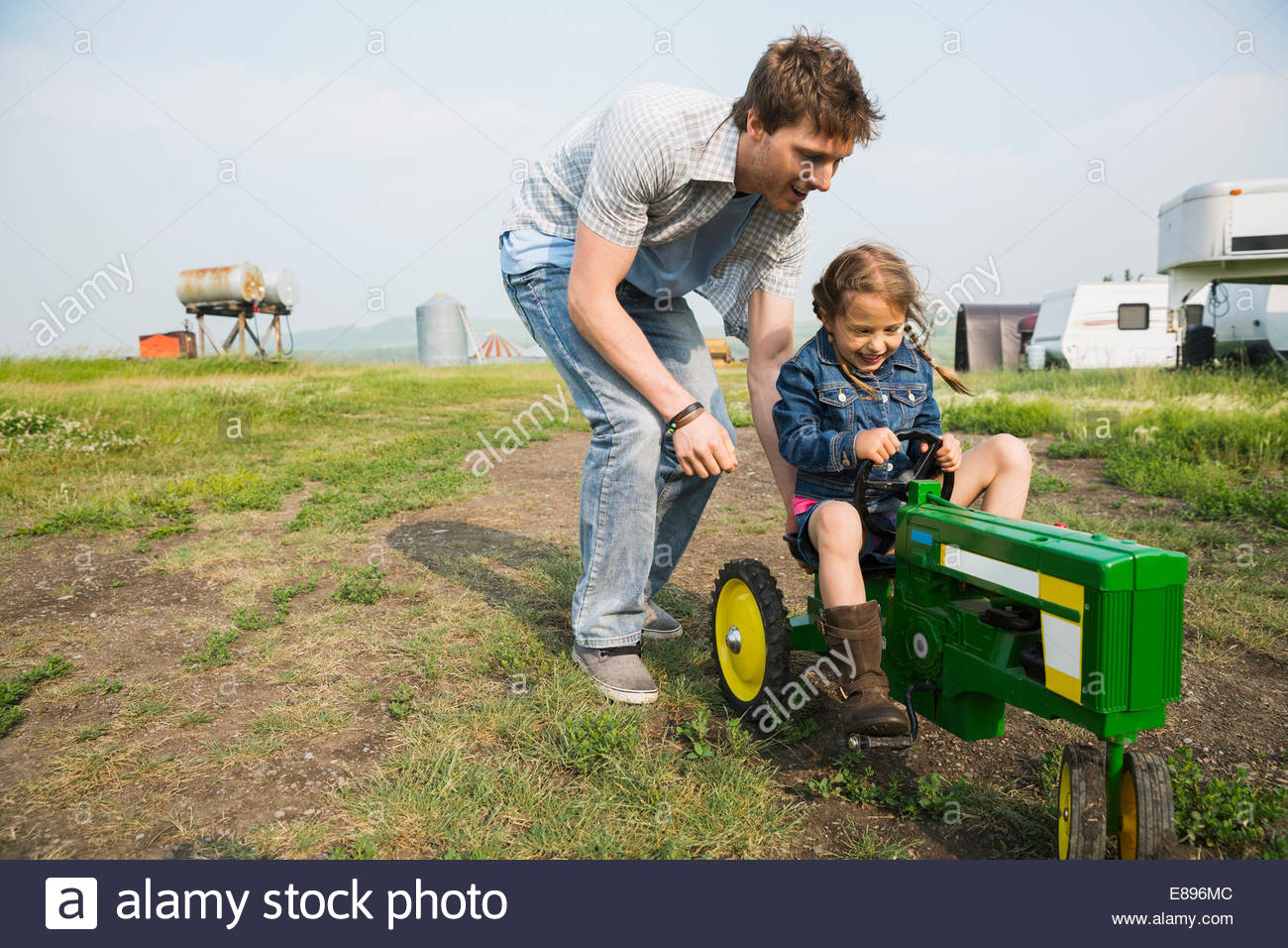 Father pushing daughter on toy tractor in field Stock Photo - Alamy
