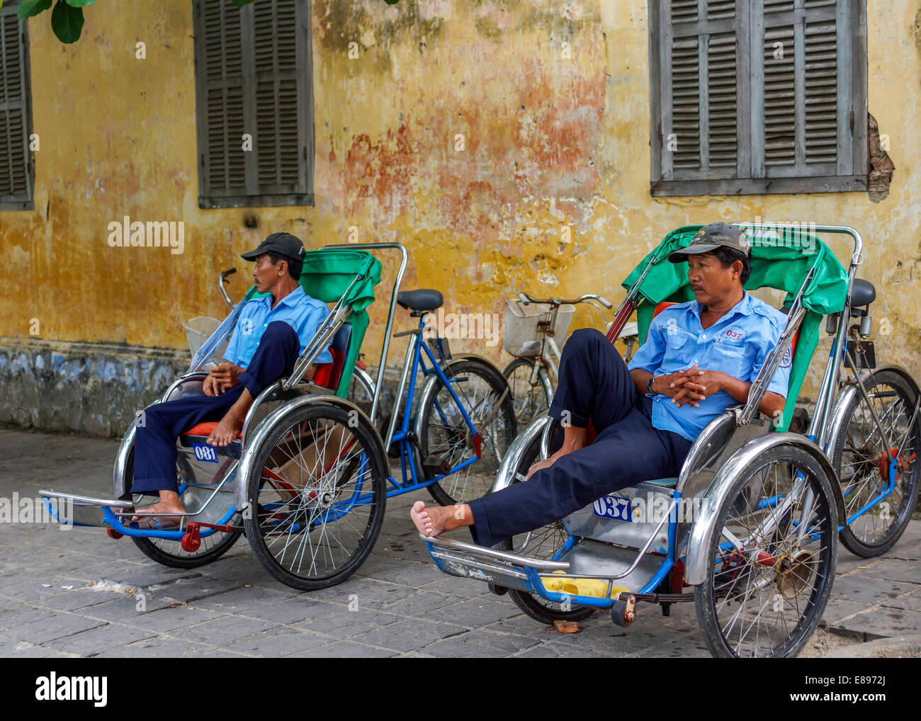 Two rickshaw drivers wait for customers while sitting in their ...