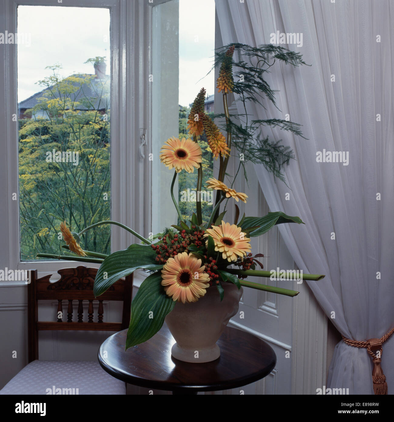 Orange gerberas and kniphofia in formal floral arrangement with green ...