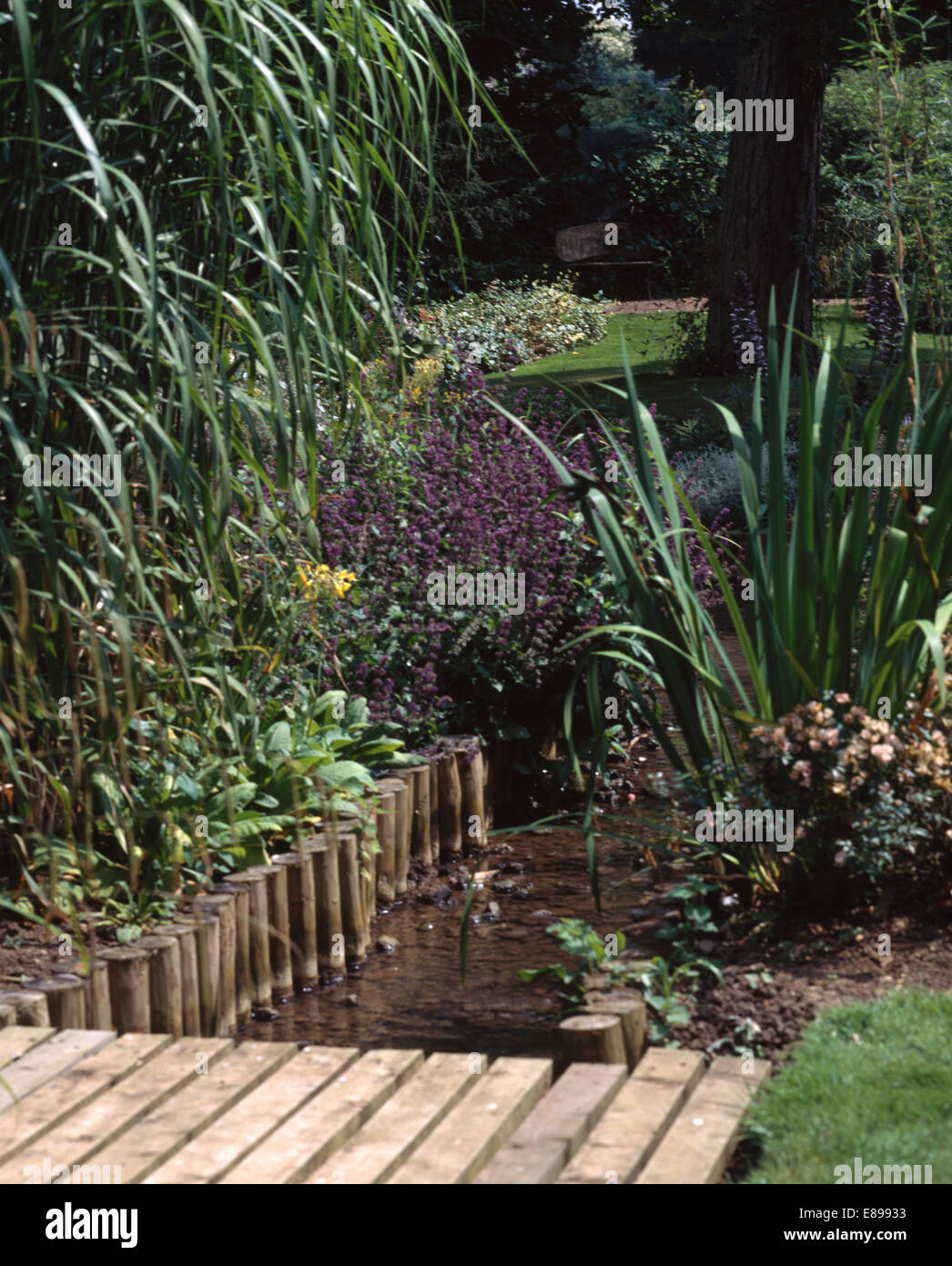 Wooden decking bridge over small garden stream with wooden edging Stock ...