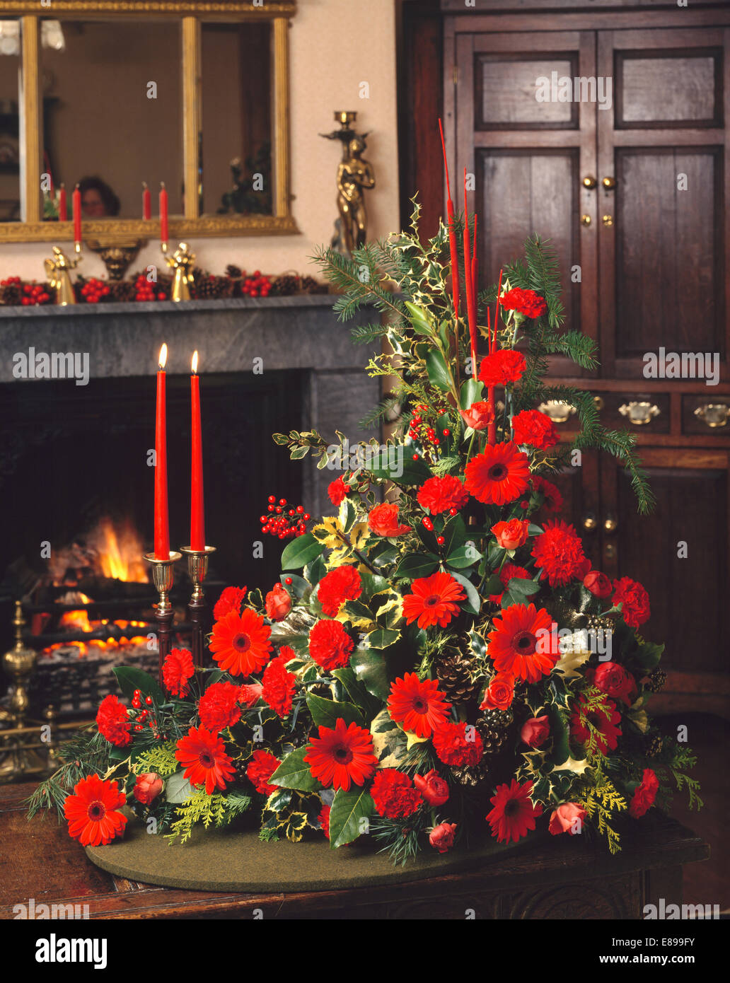 Formal floral arrangement of red gerberas and variegated holly leaves ...