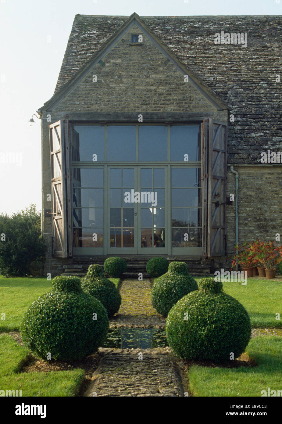 Clipped box balls on either side of path to barn conversion Stock Photo ...