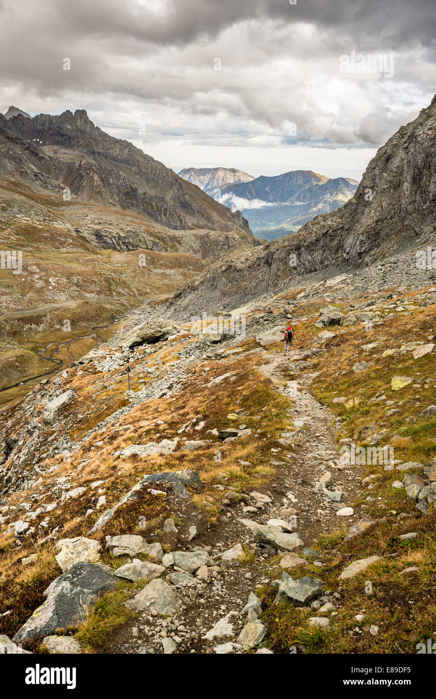 Hiker walking on dangerous footpath crossing a steep rocky slope with ...
