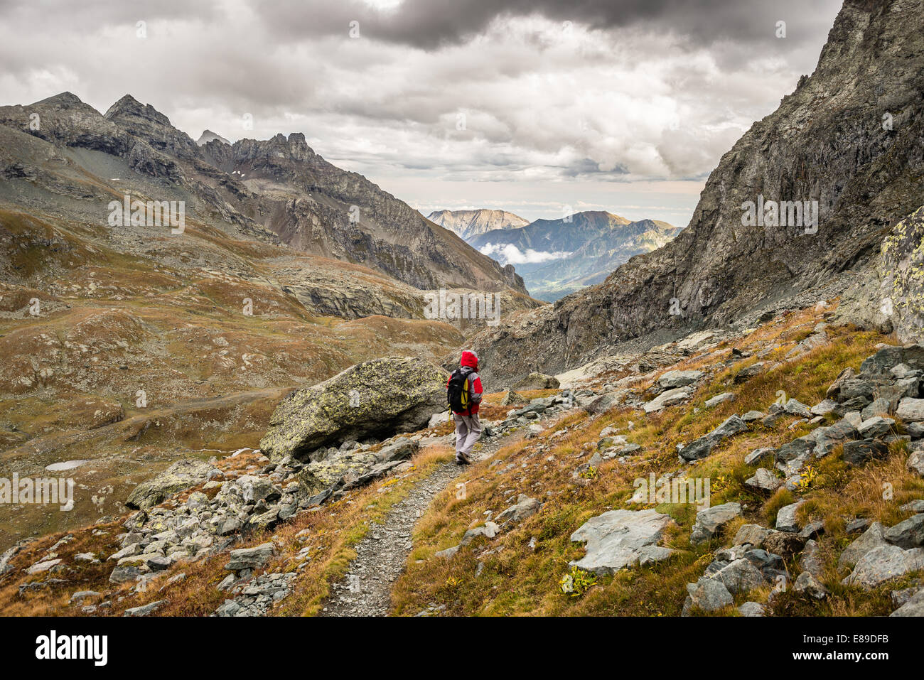 Hiker walking on dangerous footpath crossing a steep rocky slope with ...