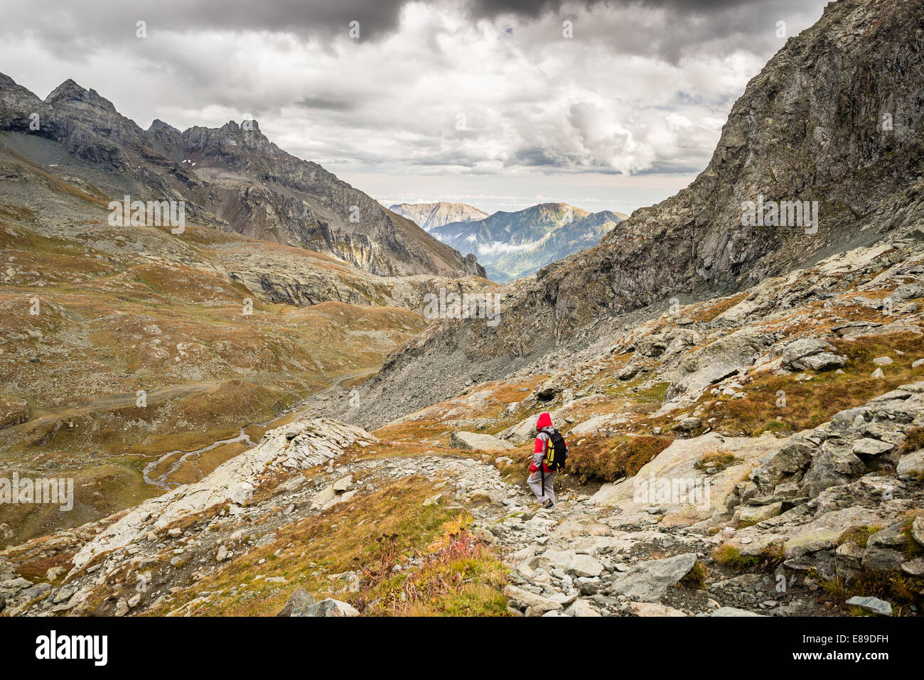 Hiker walking on dangerous footpath crossing a steep rocky slope with ...