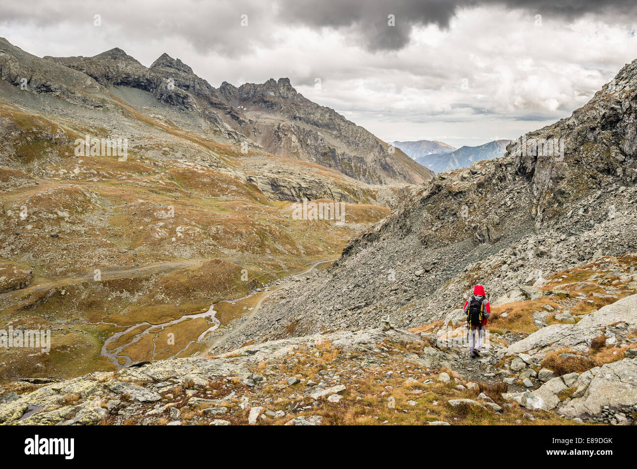 Hiker walking on dangerous footpath crossing a steep rocky slope with ...