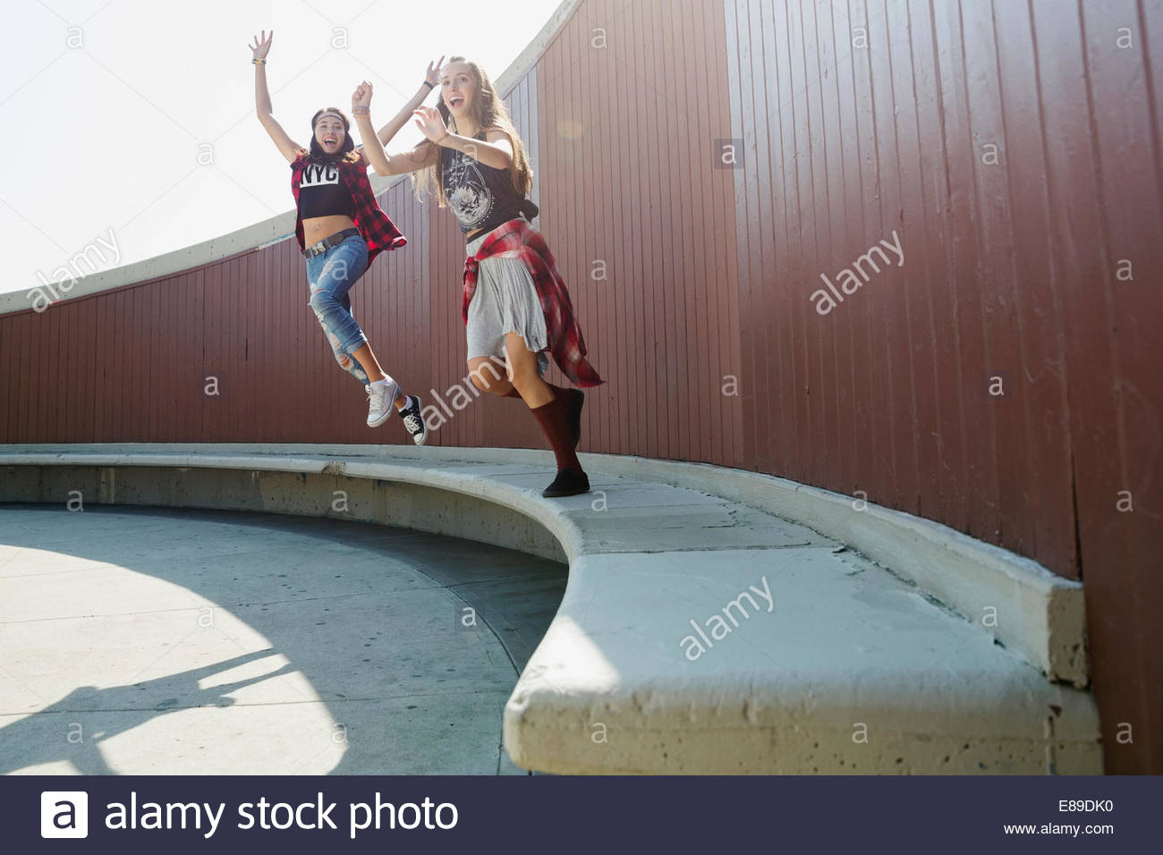 Teenage girls jumping off bench Stock Photo - Alamy