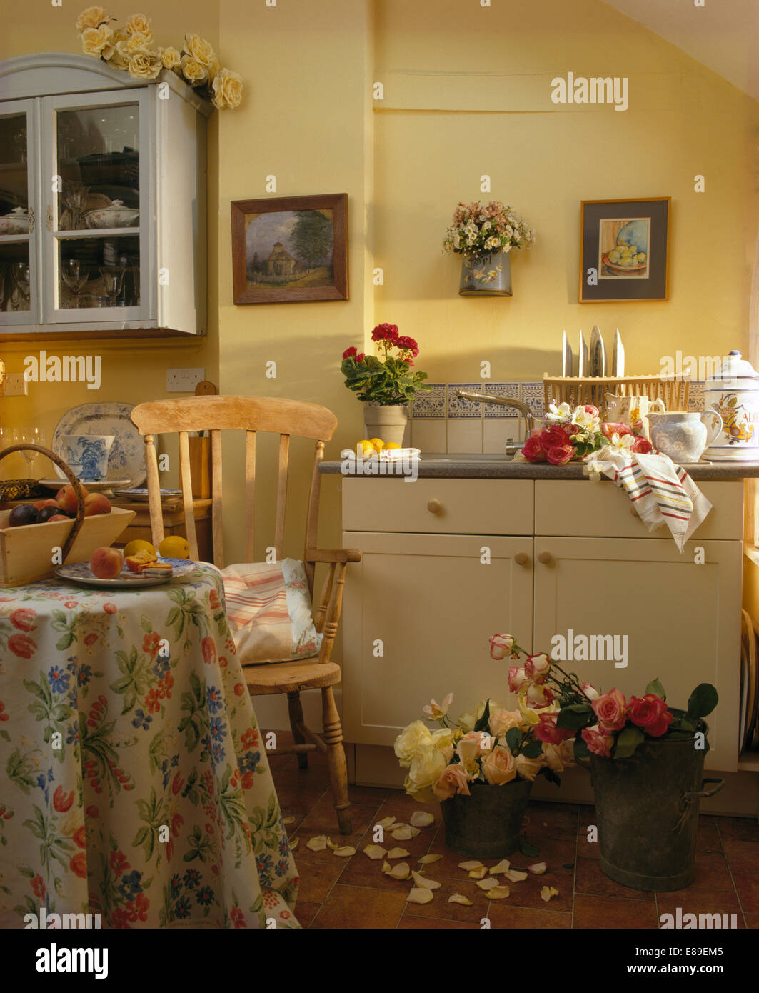 Buckets of roses on floor beside sink in cottage kitchen with stripped ...