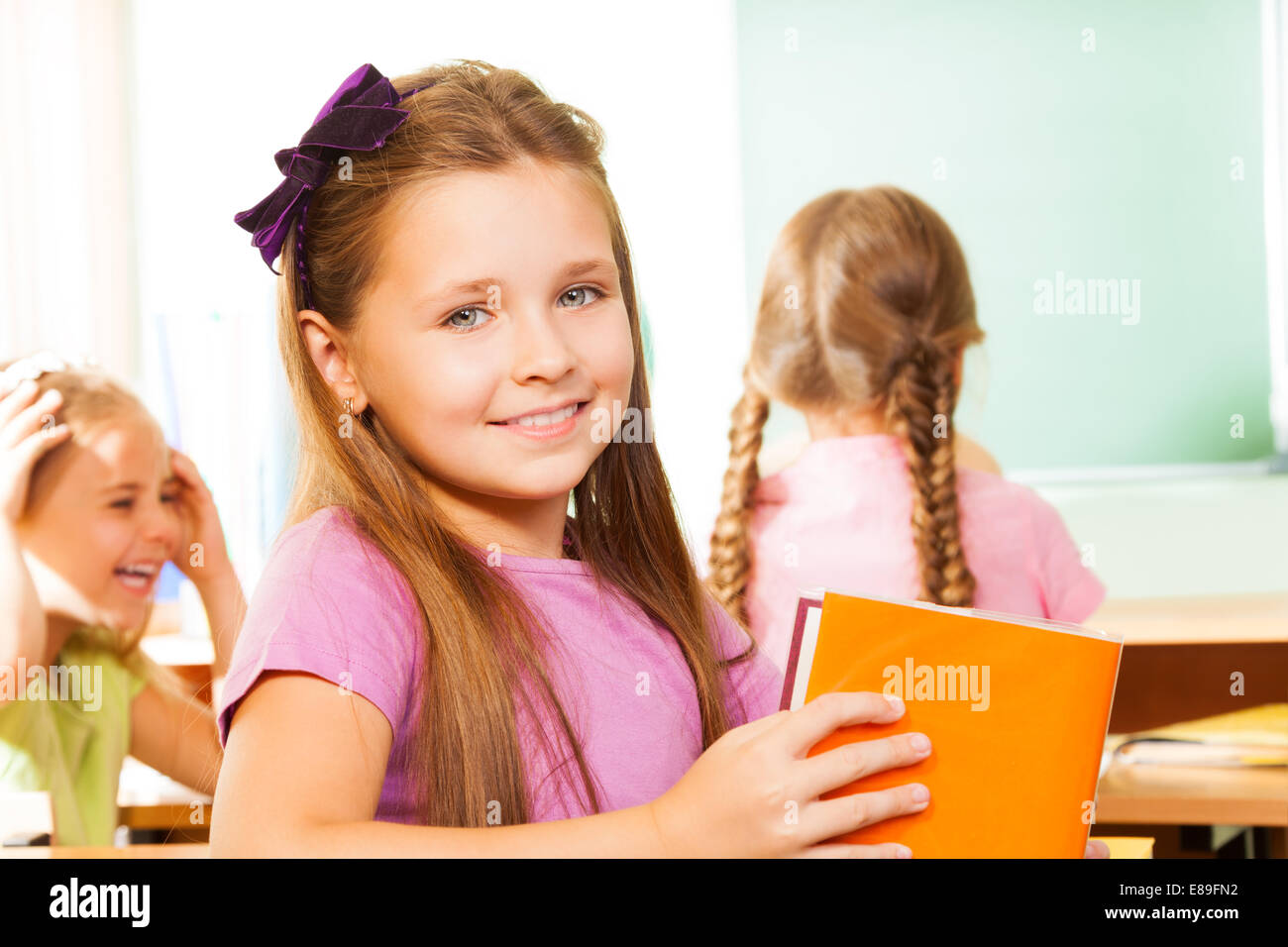 Beautiful girl with bow looking back in class Stock Photo - Alamy